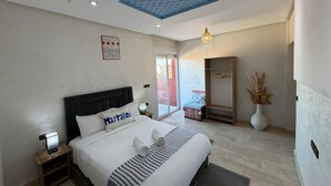 Quarto de hotel moderno com uma cama grande, mesa de cabeceira, guarda-roupa e vista exterior.