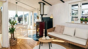 Uma sala de estar aconchegante com lareira, móveis de vime e vista para o exterior.