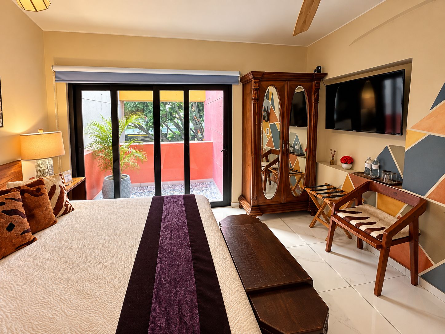 Quarto de hotel com cama, televisão, armário de madeira e varanda com vista.
