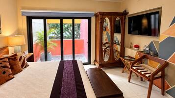 Quarto de hotel com cama, televisão, armário de madeira e varanda com vista.