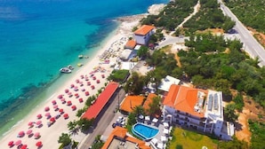 Vista aérea de um resort à beira-mar, com praia, piscina e vários edifícios.