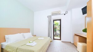 Quarto de hotel com cama, escrivaninha, cadeira e varanda pequena.