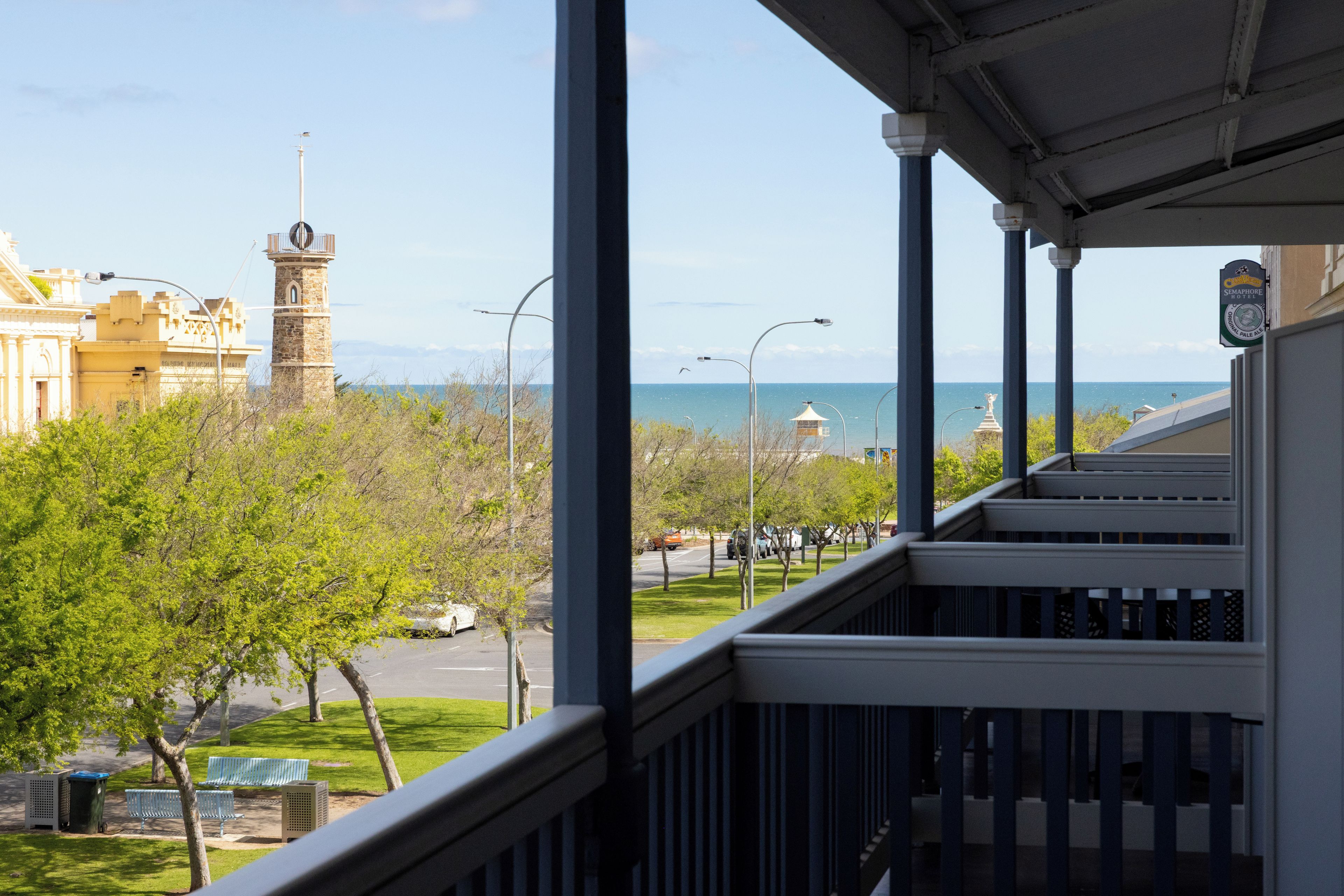 Varanda com vista para a costa, incluindo um farol e a placa de um hotel.