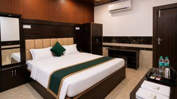 Quarto de hotel com uma cama, uma mesa de trabalho com cafeteira e um minibar.