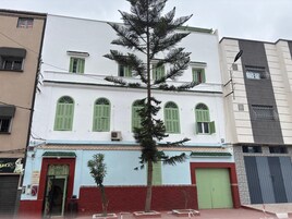 Um edifício de dois andares com persianas verdes e uma porta vermelha.