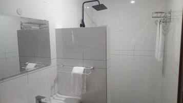 Uma casa de banho moderna com chuveiro, sanita, lavatório e porta-toalhas.