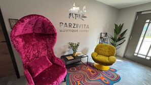 Um interior moderno com uma cadeira rosa vibrante, um poltrona amarela e um tapete colorido.