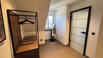 Um corredor com um banco de madeira, um porta-roupas e uma porta deslizante.