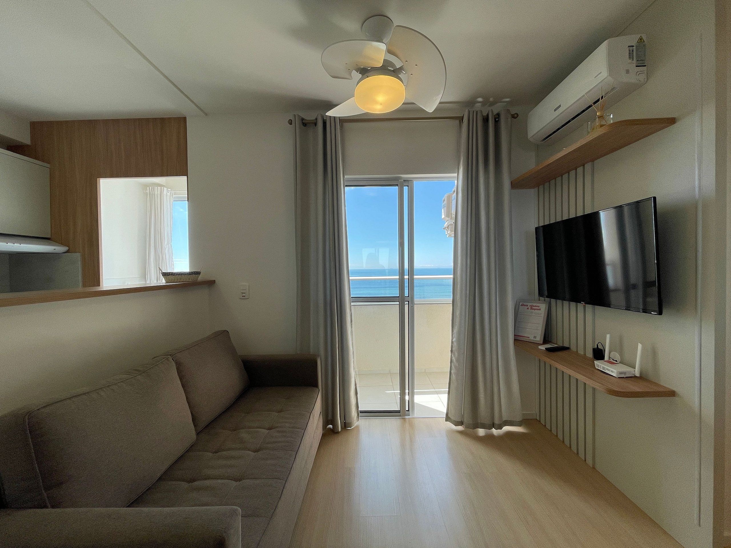 Uma sala de estar moderna com um sofá, uma TV de tela plana e um ventilador de teto.