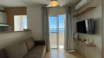 Uma sala de estar moderna com um sofá, uma TV de tela plana e um ventilador de teto.