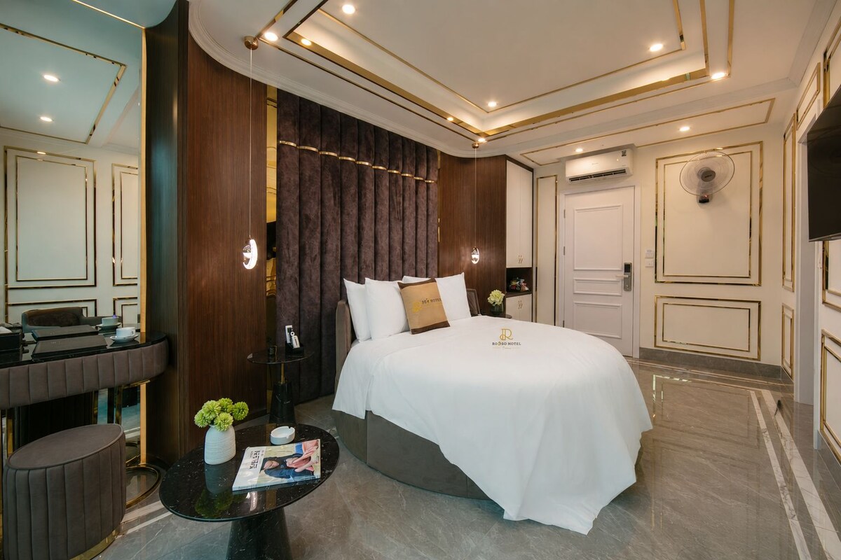 Quarto de hotel com cama, mesa de cabeceira e escrivaninha com cadeira.