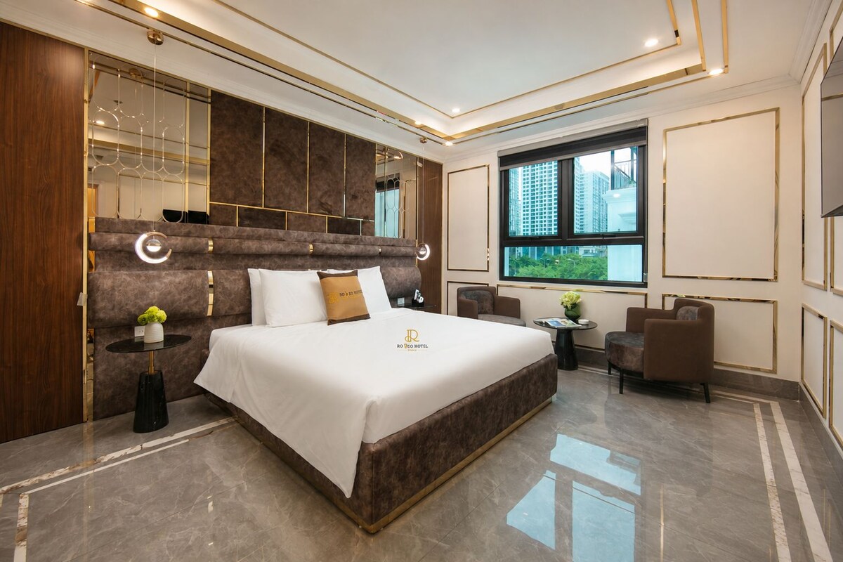 Quarto de hotel moderno com cama grande, área de estar e vista para a cidade.