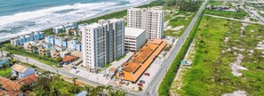 Uma área costeira com um grande complexo hoteleiro, incluindo edifícios altos e um prédio longo com telhado vermelho.