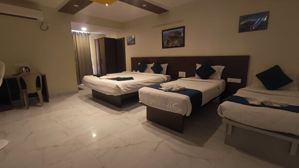 Quarto de hotel com três camas, uma escrivaninha e uma cadeira.