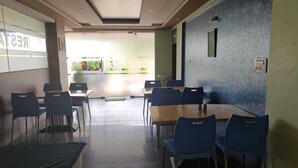 Um restaurante com mesas, cadeiras e um balcão, além de vista para o exterior.