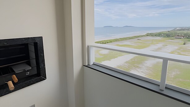 Quarto com vista para uma praia e montanhas ao longe.