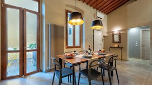 Uma sala de jantar com uma mesa de madeira, quatro cadeiras e duas luminárias pendentes.