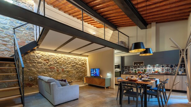 Decoração moderna com parede de pedra, um sofá, área de jantar e cozinha.