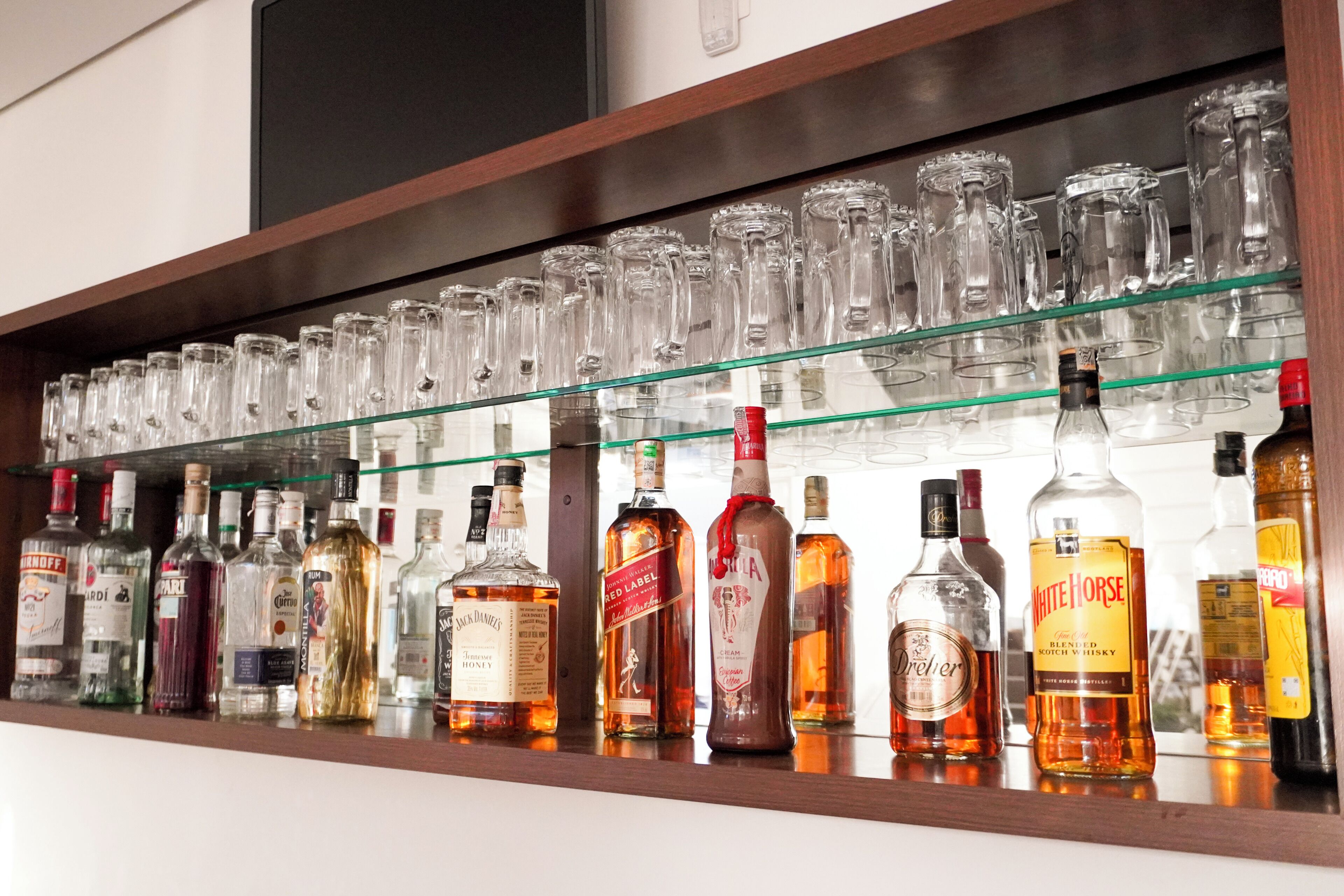 Uma área de bar com várias garrafas de bebidas e um suporte para copos.