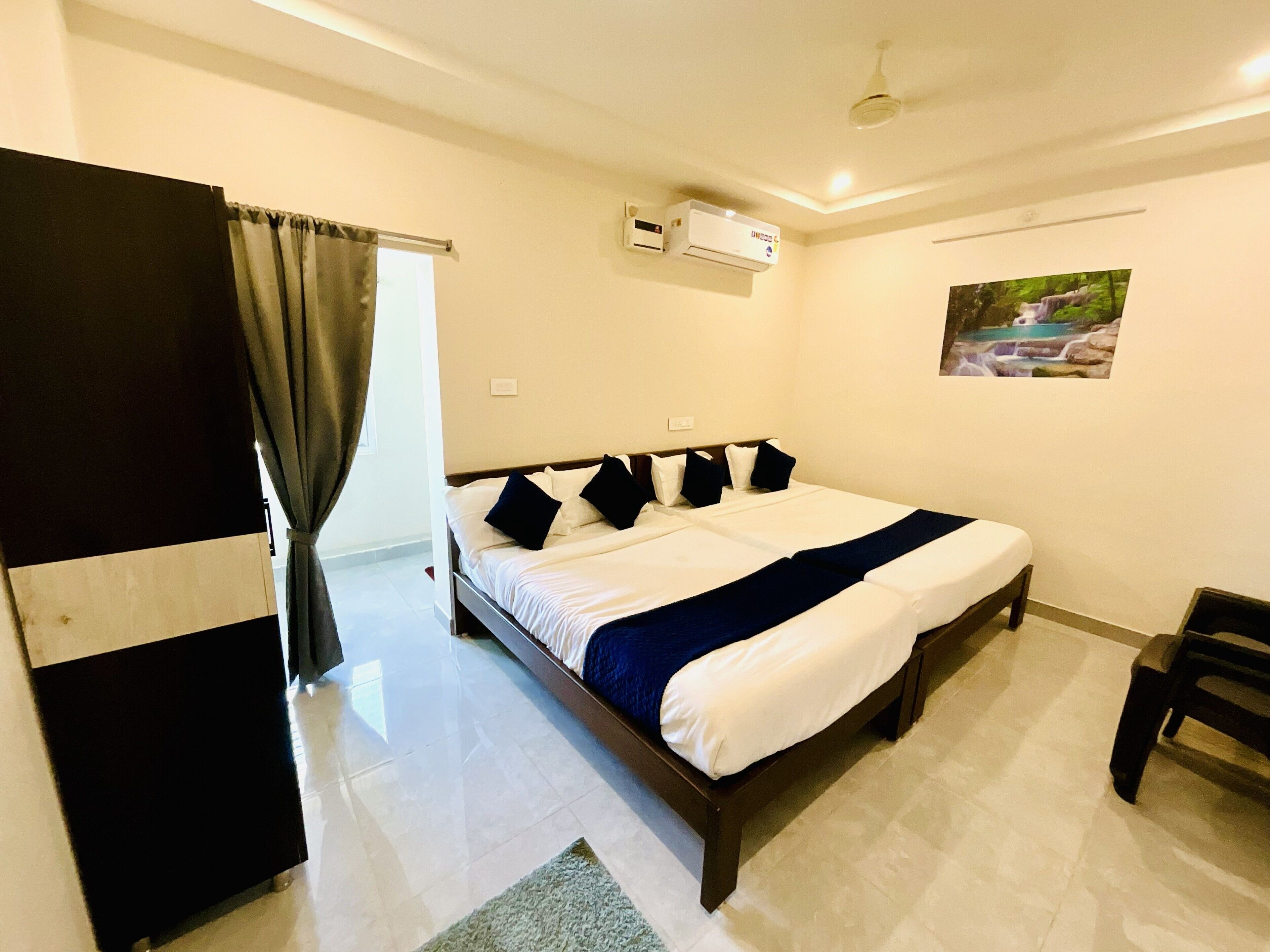 Quarto de hotel com cama, aparelho de ar condicionado e um quadro na parede.