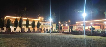 Um edifício com entrada bem iluminada, área pavimentada e algumas árvores.