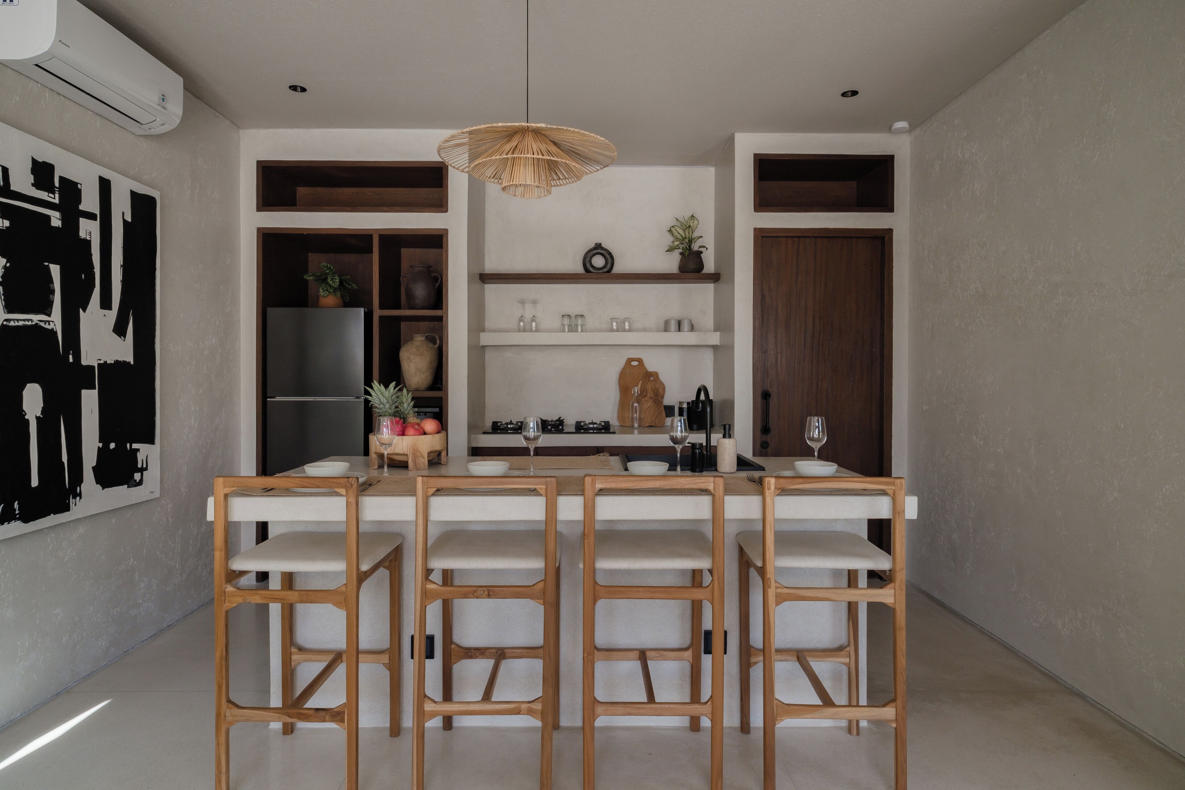 Cozinha moderna com ilha central, banquetas e luminária pendente.