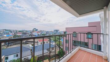 Uma varanda com vista para uma área residencial, incluindo casas e um edifício cor-de-rosa.