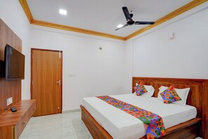 Quarto com cama de madeira, ventilador de teto, TV fixada na parede e guarda-roupa de madeira.