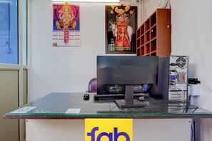 Uma mesa de receção com um computador, um calendário e uma estante com livros.