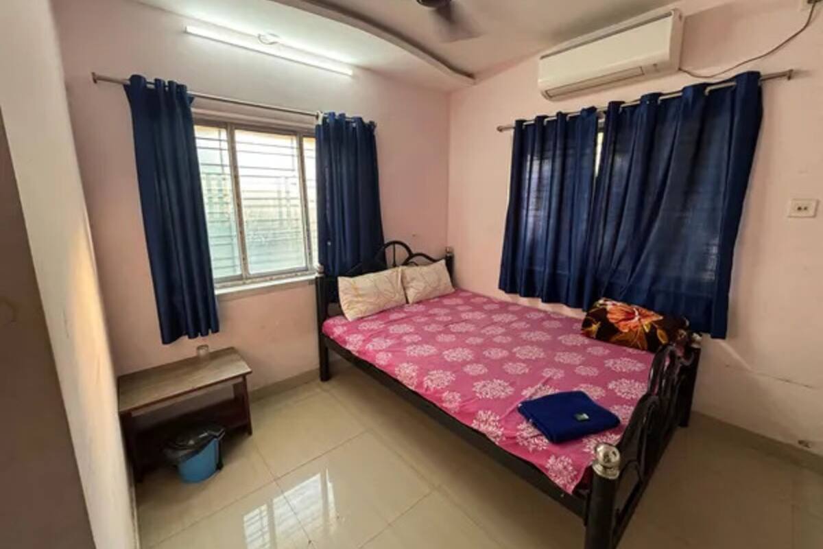 Quarto com cama, janela com cortinas, ventilador de teto e aparelho de ar condicionado.