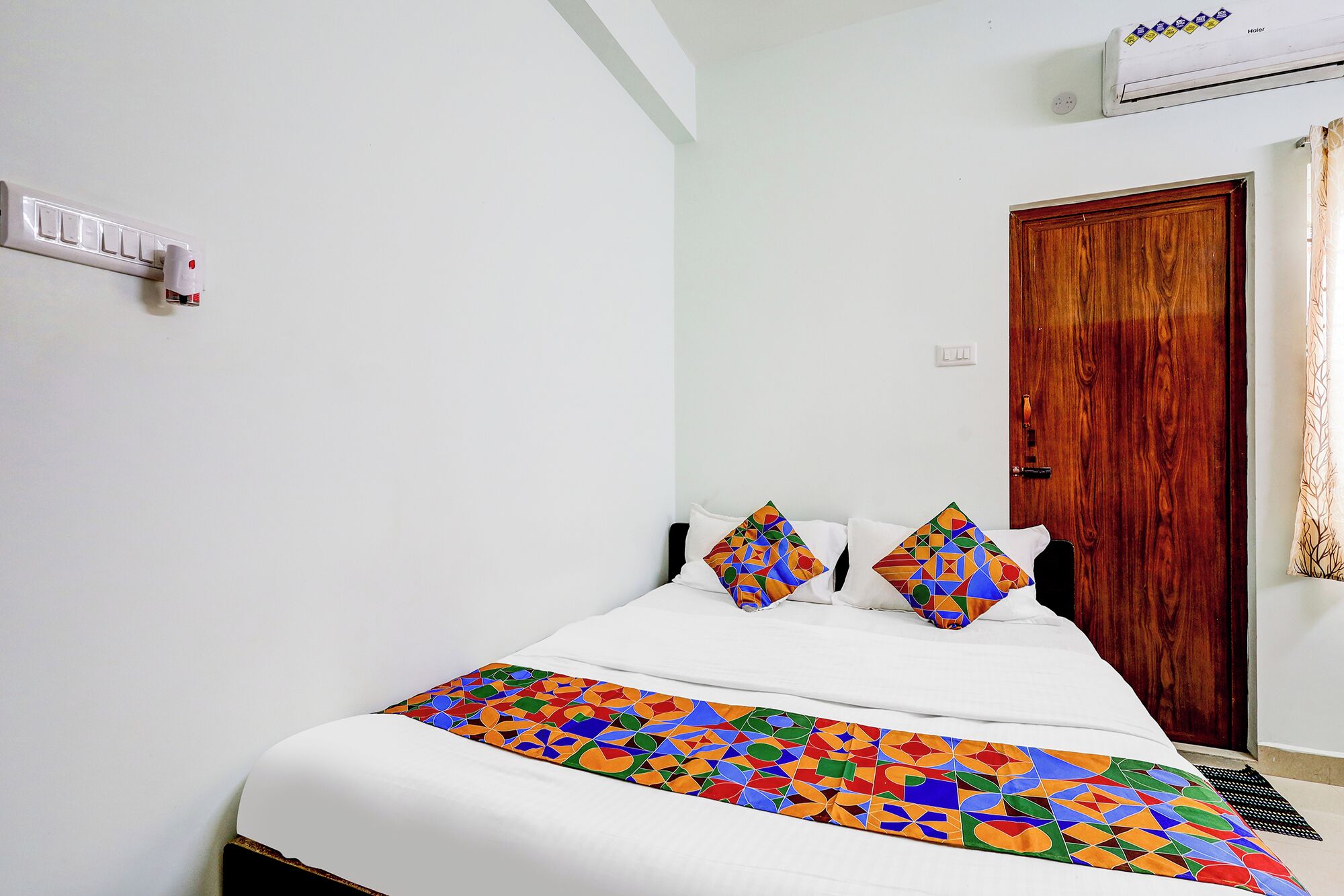 Quarto com uma cama, porta de madeira e ar condicionado.