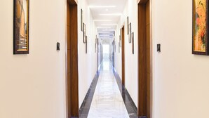 Um corredor comprido e estreito com portas de madeira e quadros nas paredes.