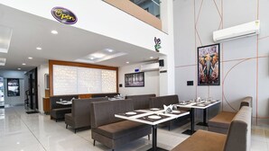 Um restaurante moderno com pé direito alto, iluminação embutida e uma combinação de assentos em cabines e mesas.