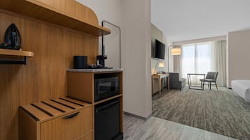Quarto de hotel com cozinha compacta, TV de tela plana, escrivaninha com cadeira e uma cama.