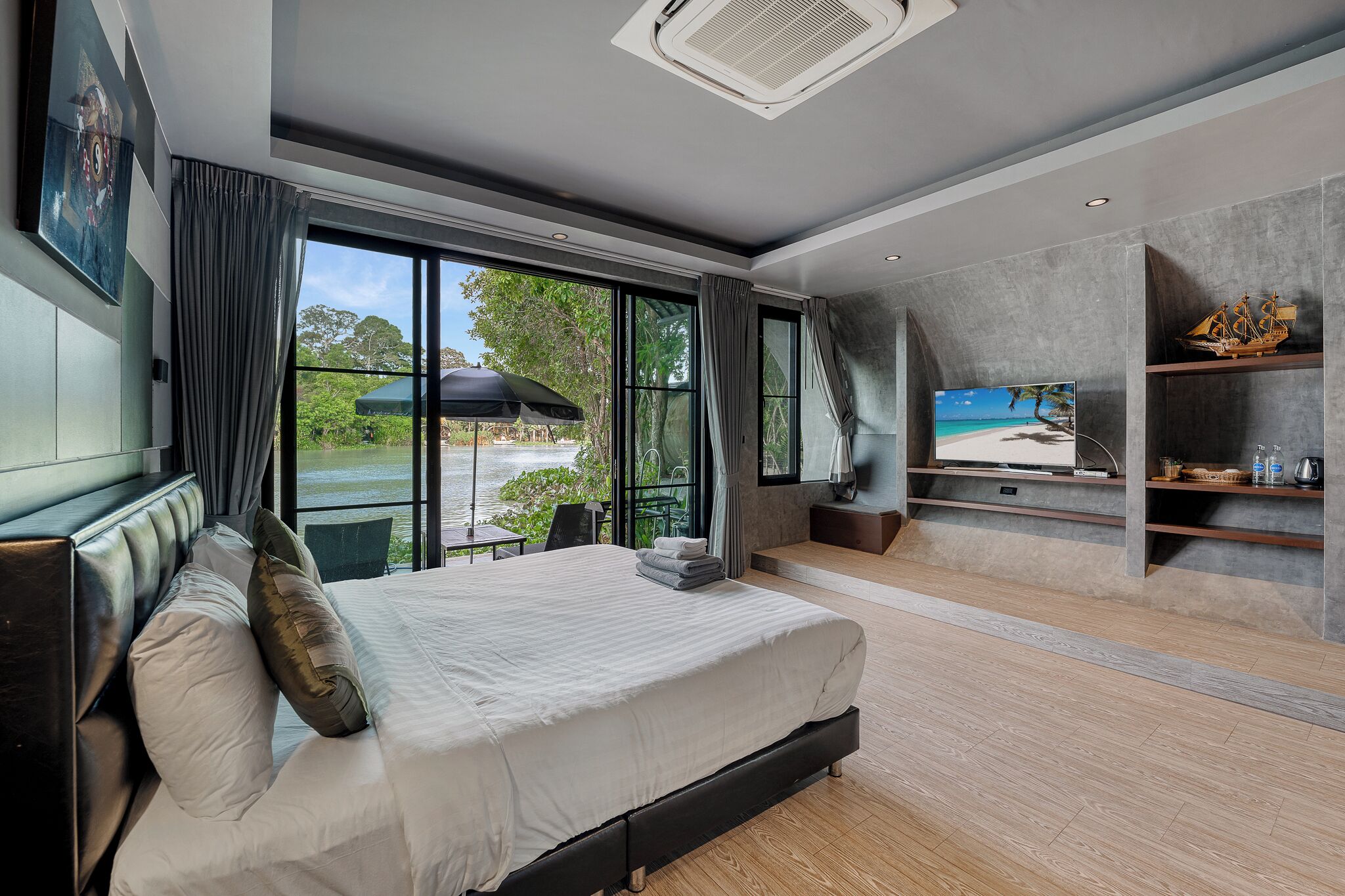 Quarto de hotel moderno com uma cama grande, televisão e vista para o exterior.