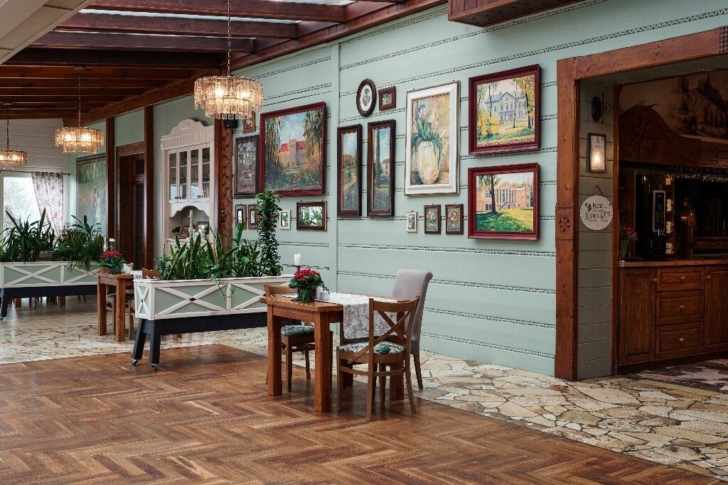 Uma sala de jantar com móveis de madeira e piso de pedra, com uma parede decorada com obras de arte emolduradas e um espaço bar com armários de madeira.