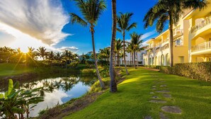 Um resort com piscina, palmeiras e um gramado bem cuidado.
