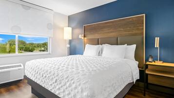 Quarto de hotel moderno com uma cama grande, vista para o verde lá fora e aquecedor embutido.