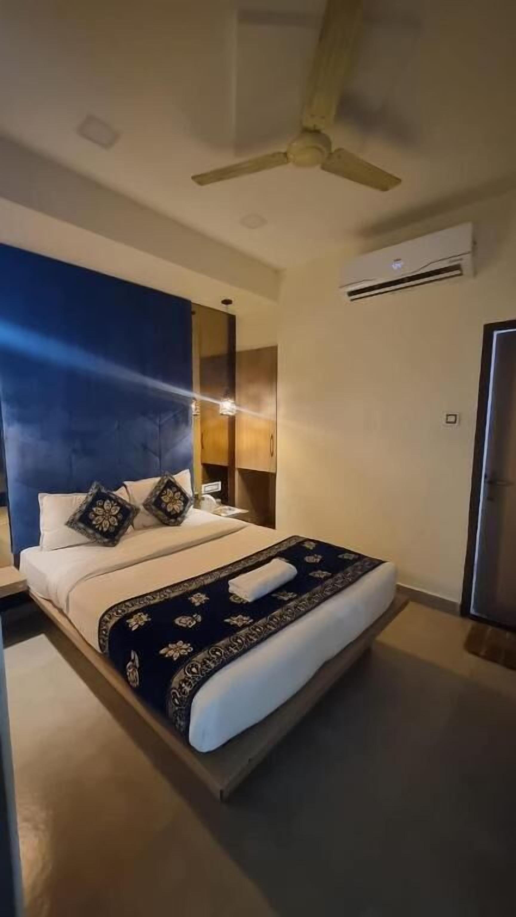 Quarto com cama, ventilador de teto, ar condicionado e porta.