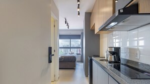 Cozinha moderna com fogão embutido, cafeteira e vista da cidade através de uma grande janela.