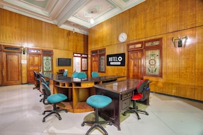Uma sala de conferências com interior em madeira, uma mesa de vidro e cadeiras azuis.