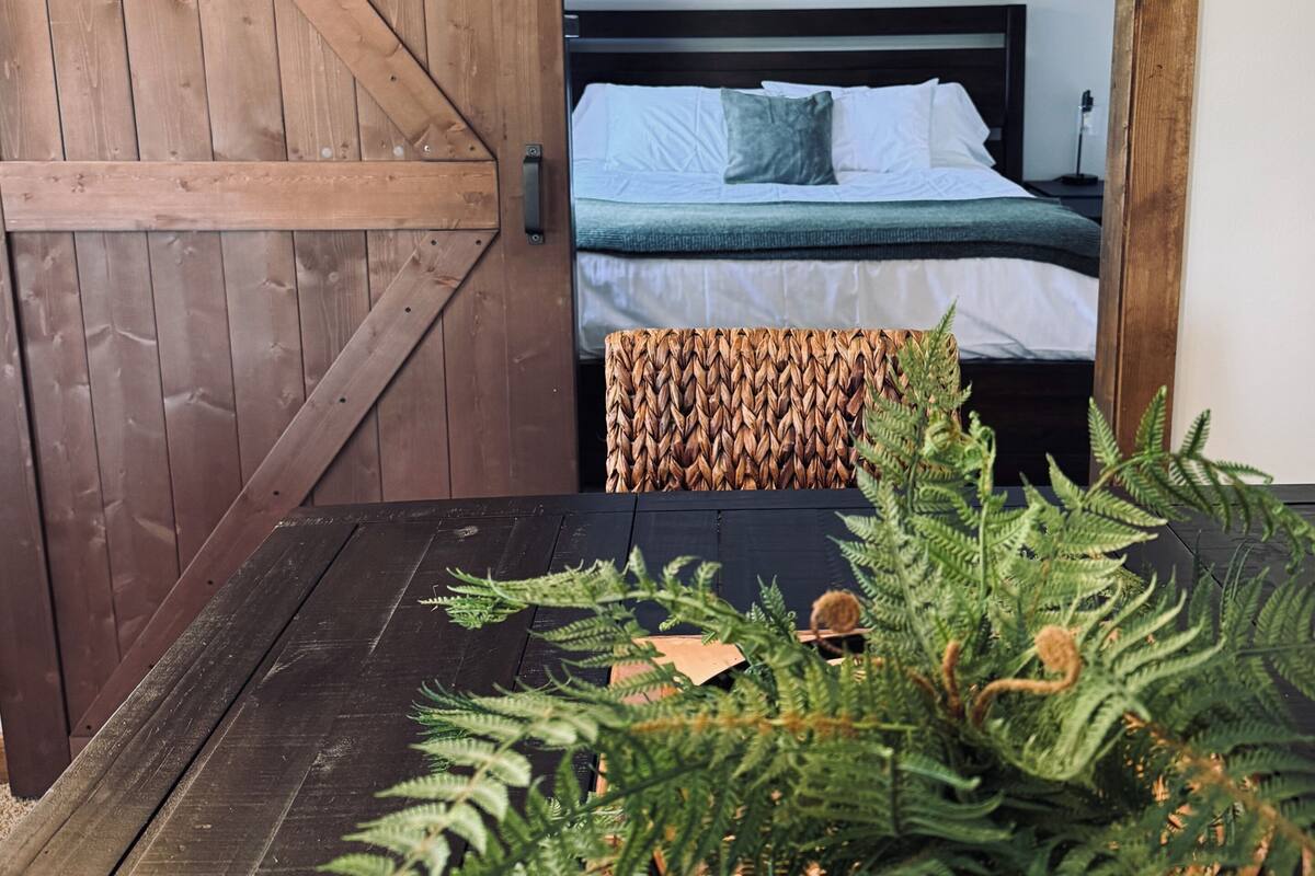 Quarto com cama, ventilador de teto e porta de madeira.