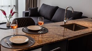 Uma cozinha moderna com bancada de mármore, pia e área de refeições com sofá e um vaso de flores.