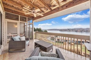 Uma varanda com mobiliário de vime, um ventilador de teto e vista para um lago.