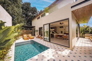 Uma casa moderna com piscina, amplas portas de vidro e um espaço de varanda.