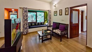 Uma sala de estar com sofá, mesa de centro e janela com cortinas.