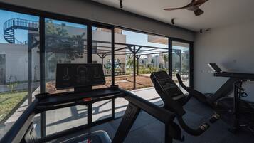 Uma academia moderna com esteira, bicicleta ergométrica e uma grande janela com vista para uma área residencial.