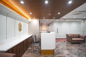 Uma área de recepção com teto de madeira, balcão de atendimento, sofá de couro marrom e piso estampado.