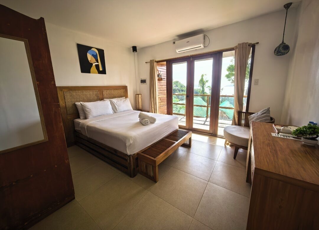 Quarto com cama, escrivaninha, cadeira, janela e porta.