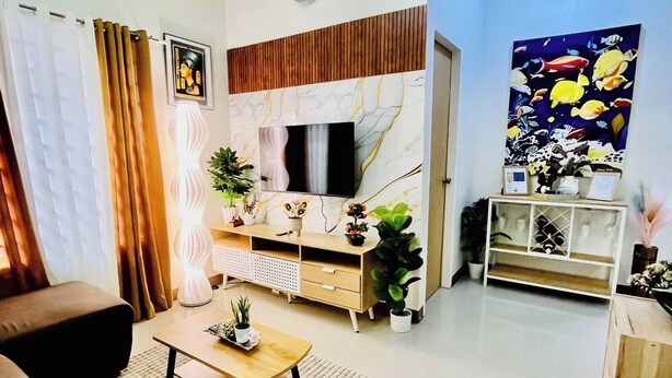 Uma sala de estar moderna com sofá, mesa de centro, TV e plantas decorativas.